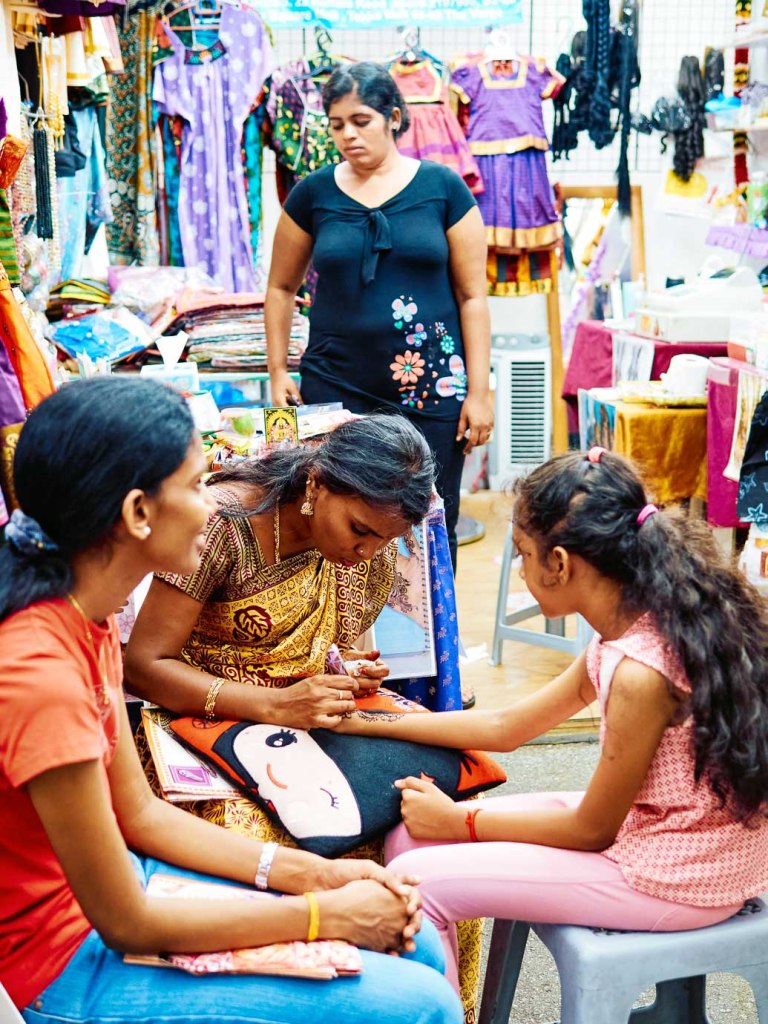 A craftswoman applying Mehndi (Henna) on a young girl’s hand, at ...
